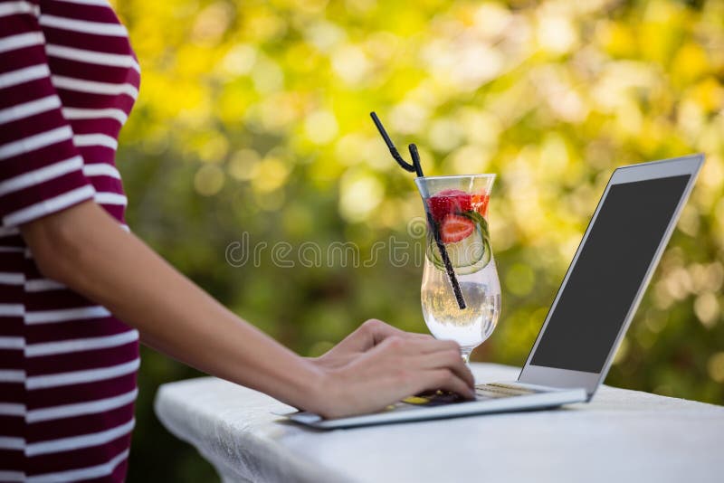 Mid Section of Woman Using Laptop by Cocktail in Restaurant Stock Photo ...