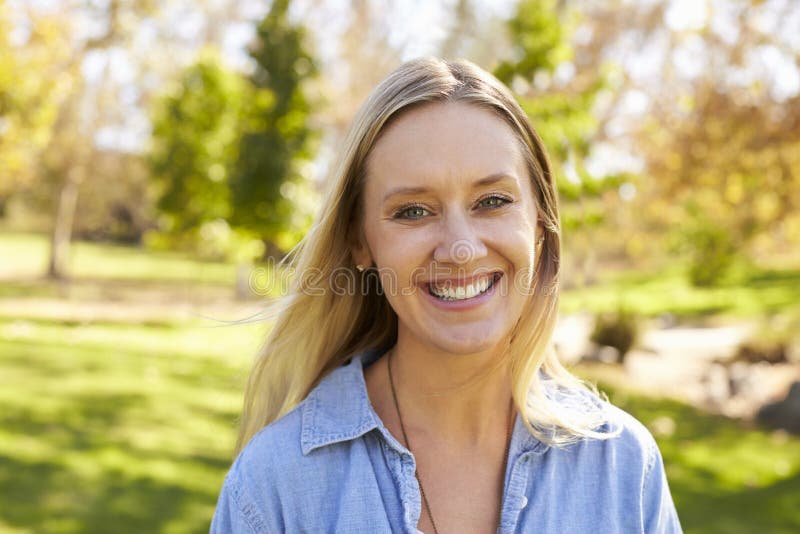 Mid Thirties White Woman Smiling To Camera in Park, Vertical Stock ...