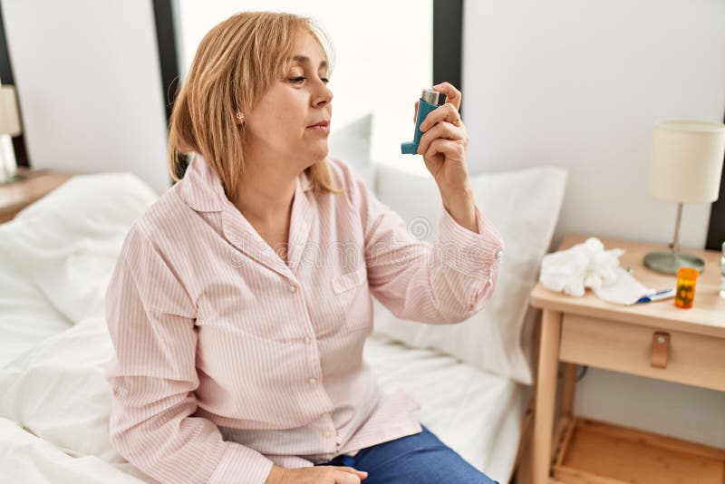 Middle Age Asthmatic Woman Using Inhaler Sitting on the Bed at Home ...