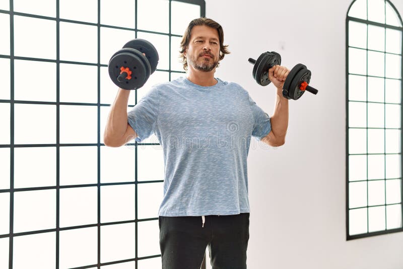 Middle Age Caucasian Man Training Using Dumbbells at Sport Center Stock ...