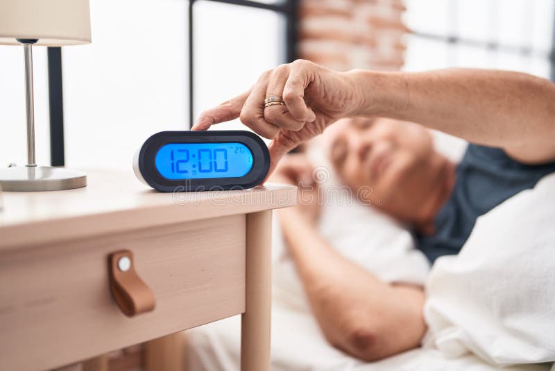 Middle Age Grey-haired Man Lying on Bed Turning Off Alarm Clock at ...