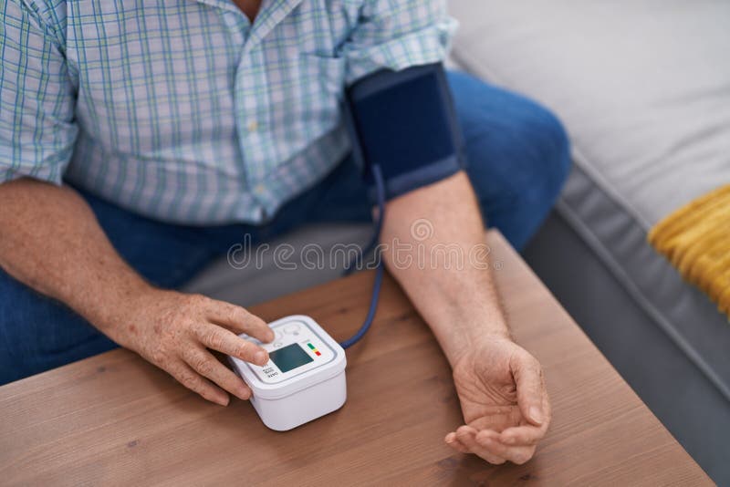 Middle Age Grey-haired Man Measuring Pulse Using Tensiometer at Home ...