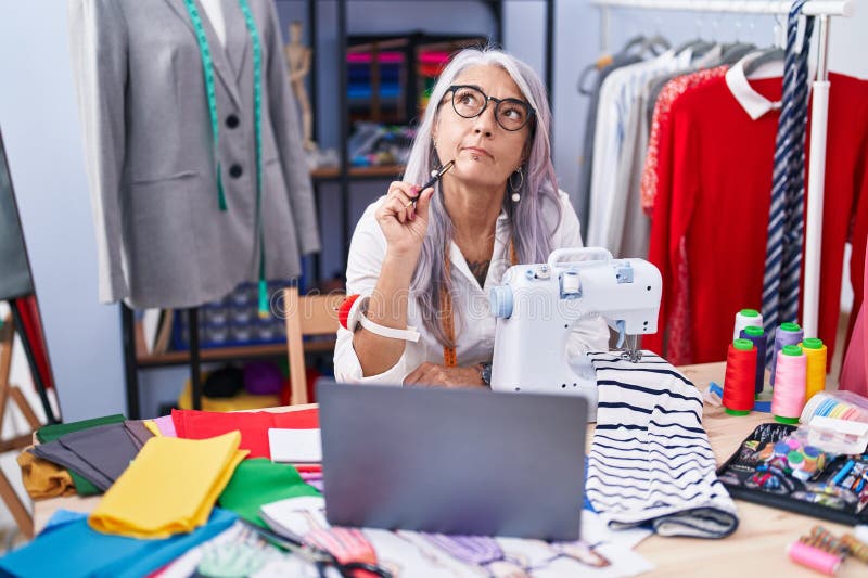 Middle Age Grey-haired Woman Tailor Using Sewing Machine and Laptop at ...