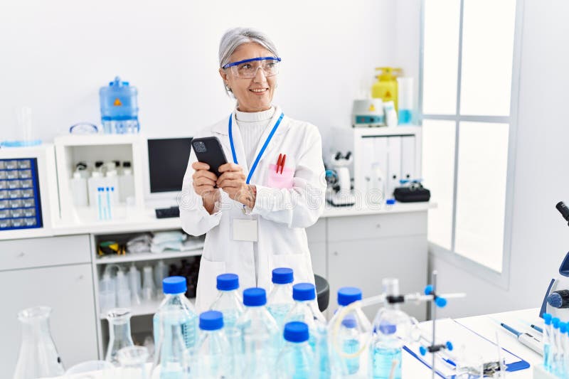 Middle Age Grey-haired Woman Wearing Scientist Uniform Using Smartphone ...