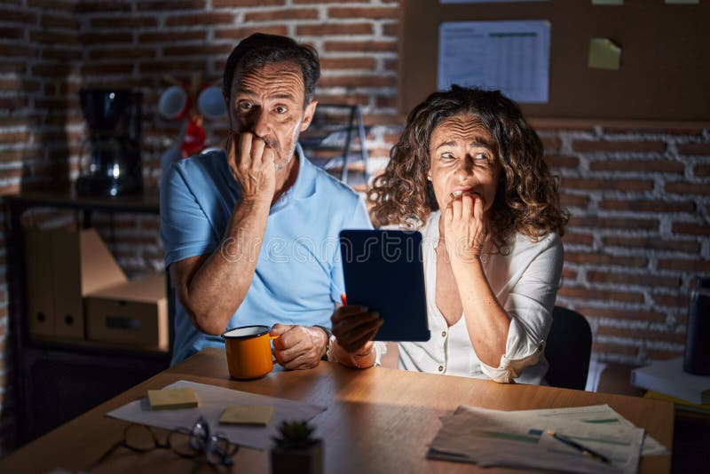Middle Age Hispanic Couple Using Touchpad Sitting on the Table at Night ...