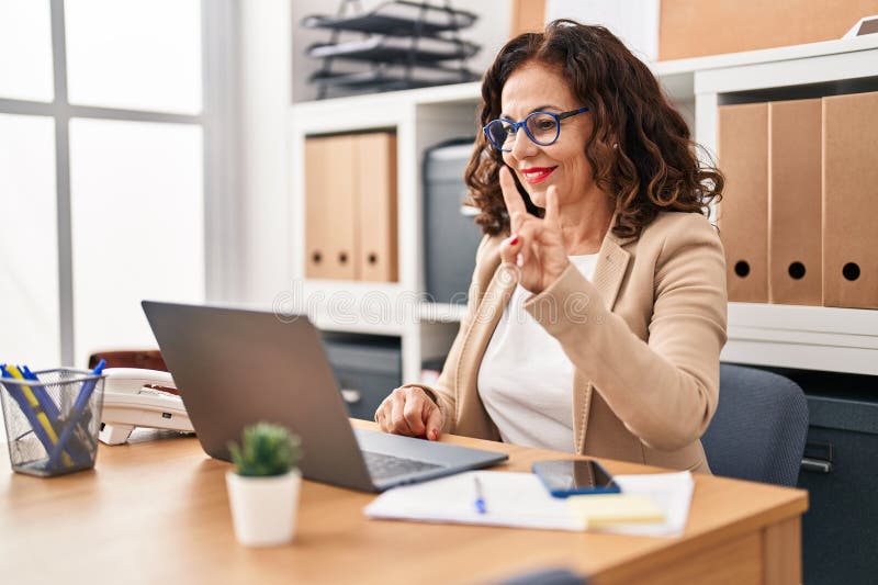 Middle Age Hispanic Woman Doing Video Call Using Sign Language at the ...