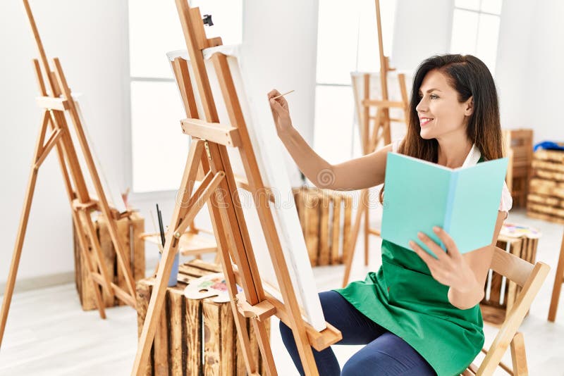 Middle Age Hispanic Woman Looking Book Drawing at Art Studio Stock ...