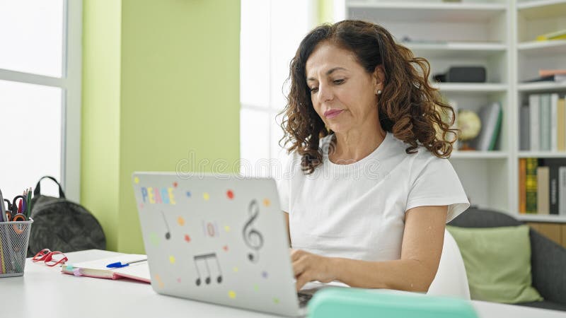 Middle Age Hispanic Woman Student Using Laptop Studying at Library ...
