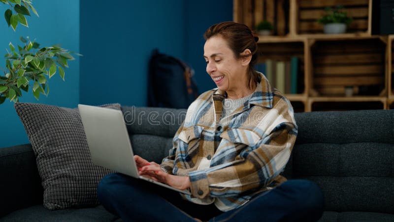 Middle Age Hispanic Woman Using Laptop Sitting on Sofa at Home Stock ...