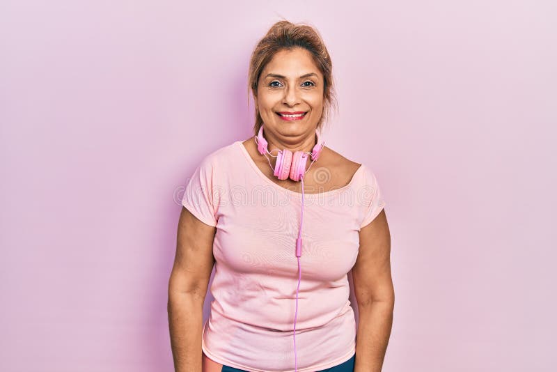 Middle Age Hispanic Woman Wearing Gym Clothes And Using Headphones With