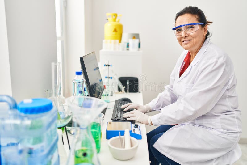 Middle Age Hispanic Woman Wearing Scientist Uniform Using Computer at ...