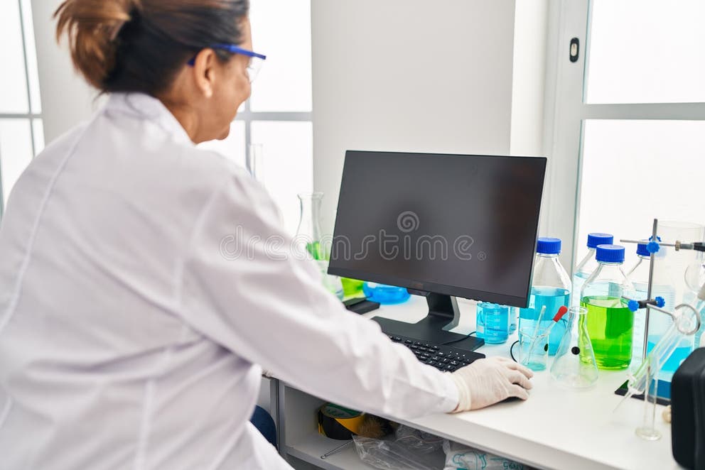 Middle Age Hispanic Woman Wearing Scientist Uniform Using Computer at ...