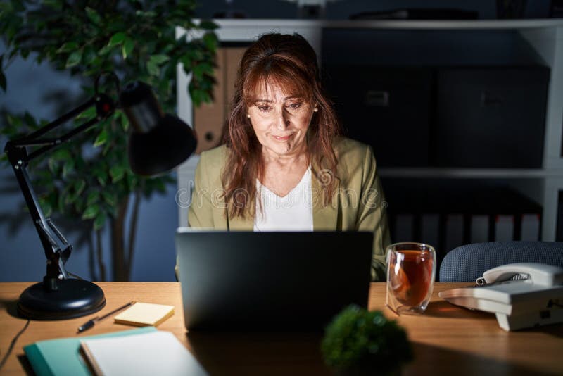 Middle Age Hispanic Woman Working Using Computer Laptop at Night ...