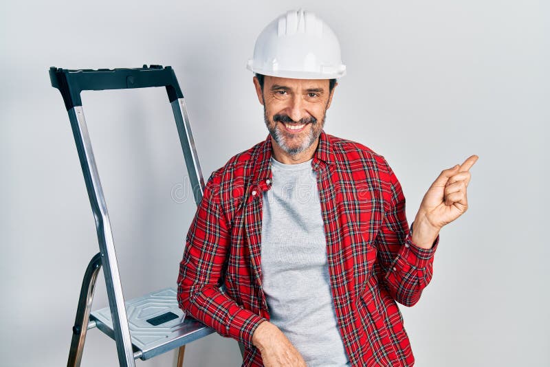 Middle Age Hispanic Worker Man Using Ladder Smiling Happy Pointing with ...