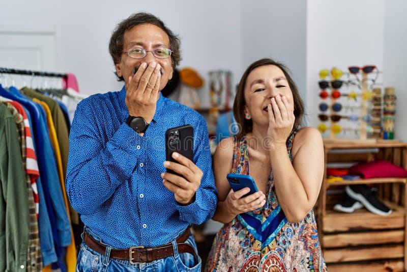 Middle Age Interracial Couple At Retail Shop Using Smartphone Laughing