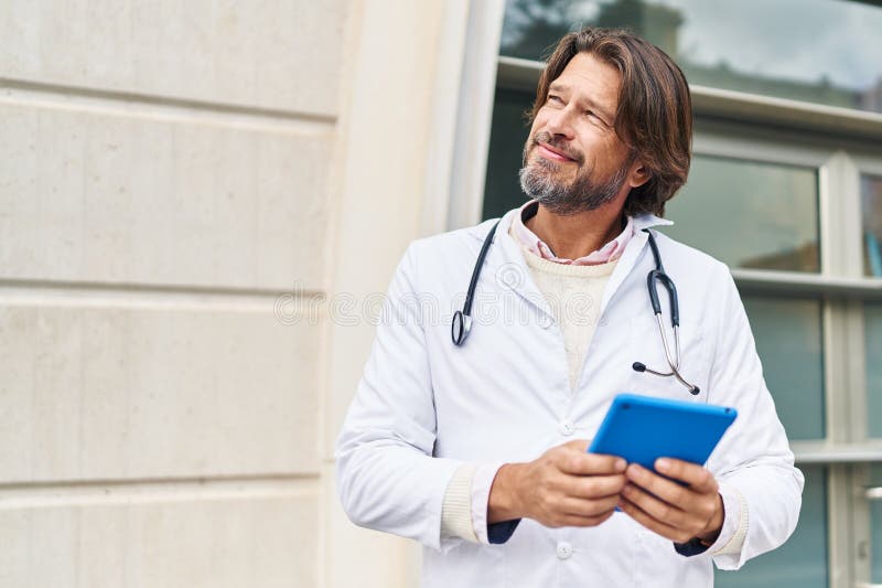 Middle Age Man Doctor Smiling Confident Using Touchpad at Hospital ...