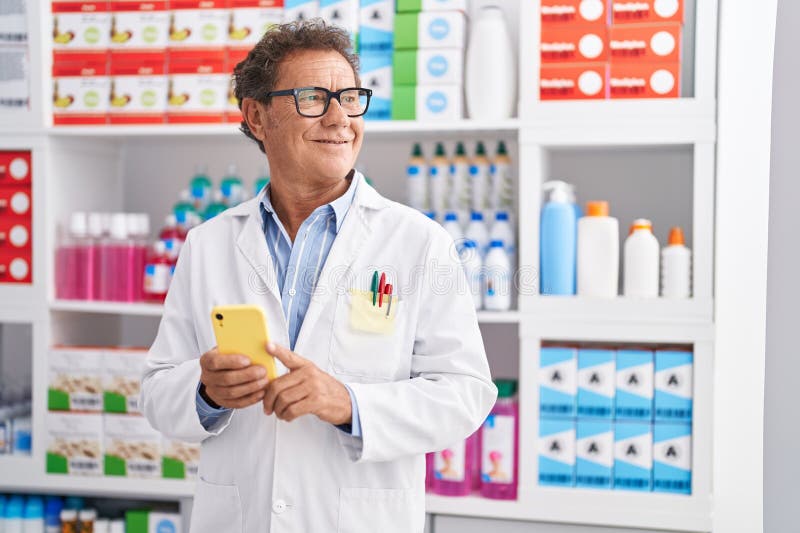 Middle Age Man Pharmacist Smiling Confident Using Smartphone at ...