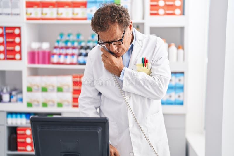 Middle Age Man Pharmacist Talking on Telephone Using Computer at ...