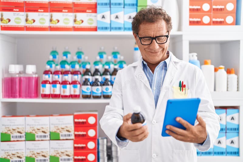 Middle Age Man Pharmacist Using Touchpad Holding Medicine Bottle at ...