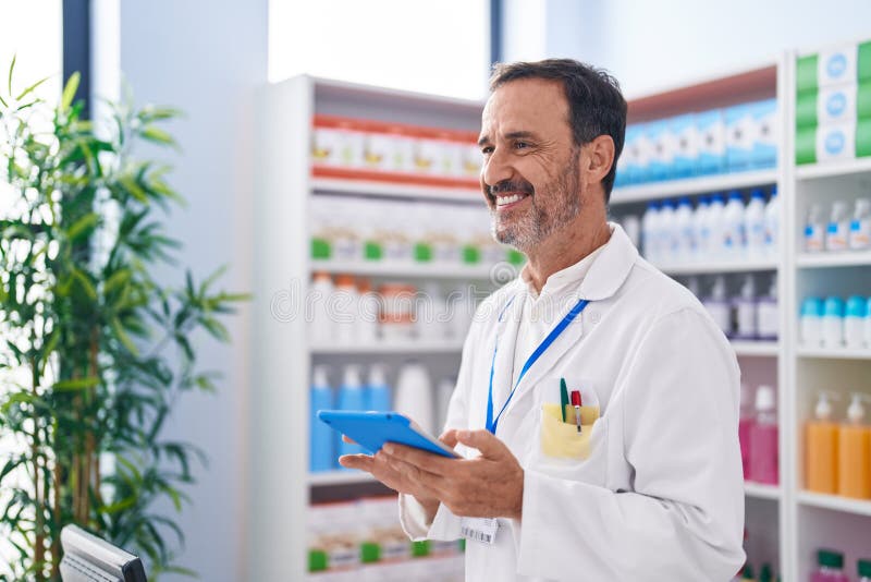 Middle Age Man Pharmacist Using Touchpad Working at Pharmacy Stock ...