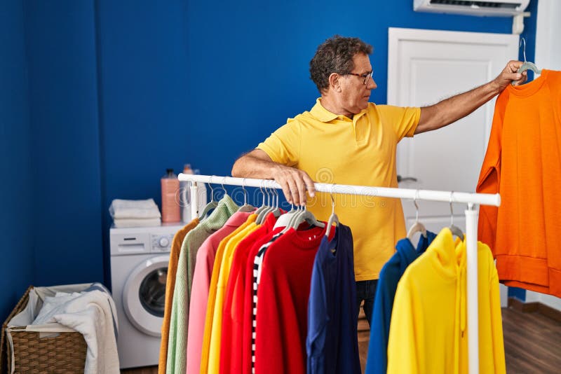Middle Age Man Smiling Confident Leaning on Clothes Rack at Laundry ...