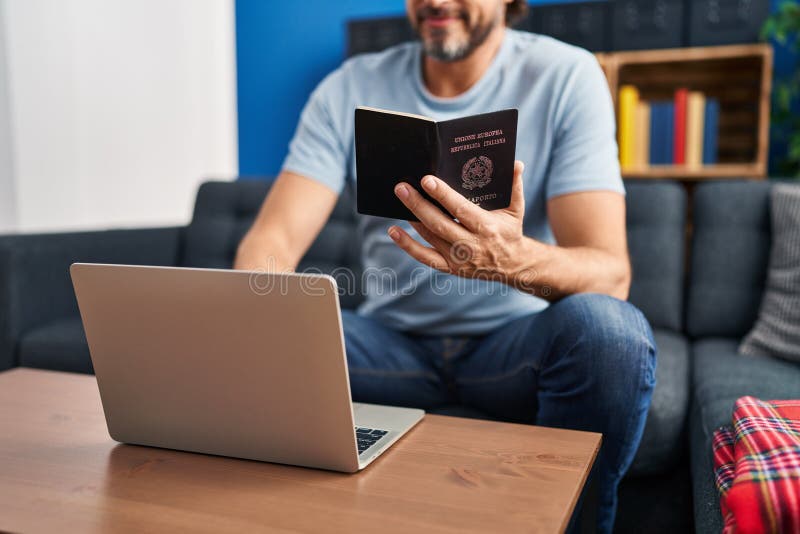Middle Age Man Using Laptop Holding Italian Passport at Home Stock ...