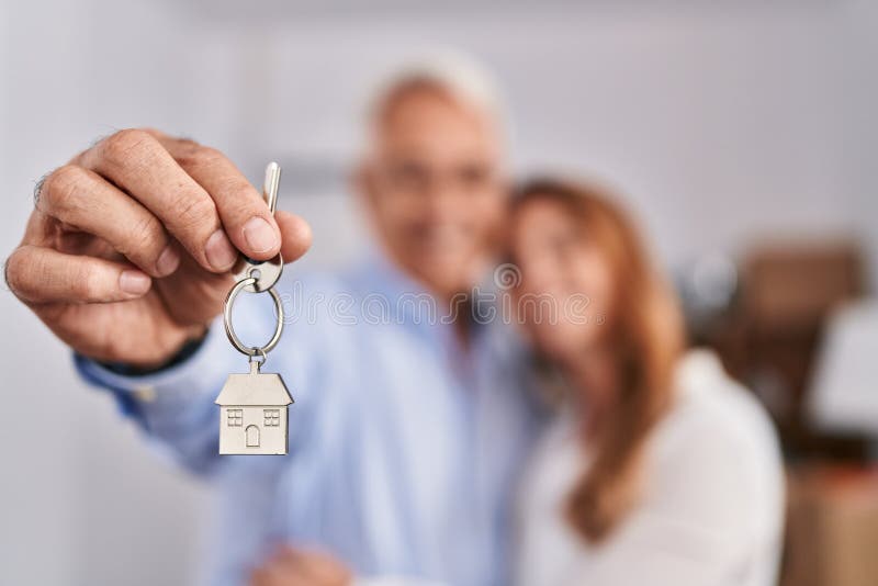 Middle Age Man And Woman Couple Hugging Each Other Holding Key Of New