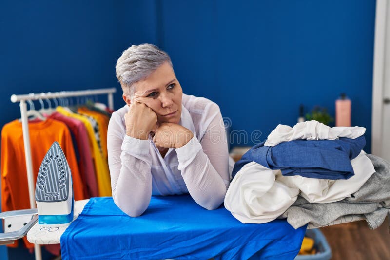 Middle Age Woman Boring Leaning on Ironing Board at Laundry Room Stock ...