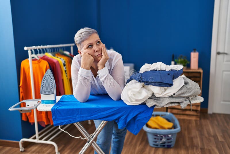 Middle Age Woman Boring Leaning on Ironing Board at Laundry Room Stock ...