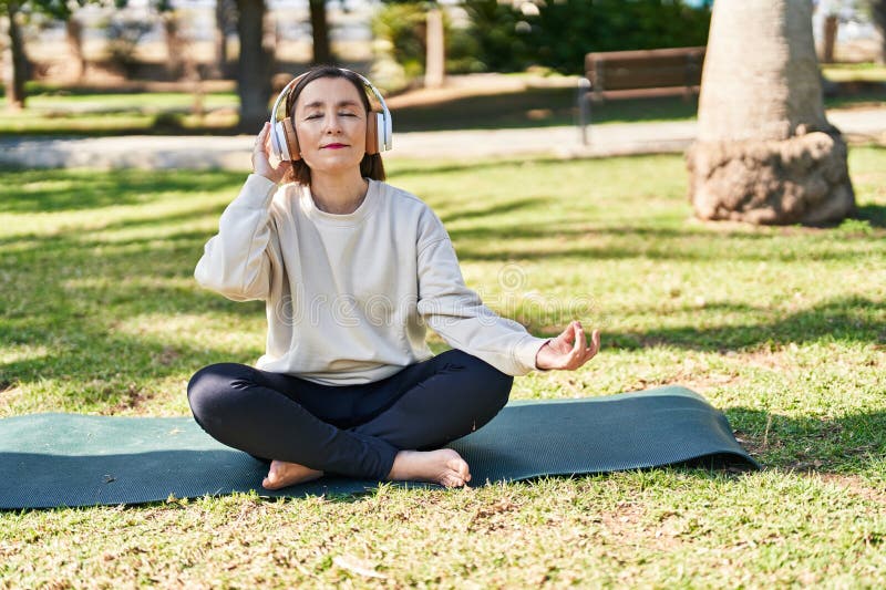Middle Age Woman Doing Yoga Exercise Sitting on Herb at Park Stock ...
