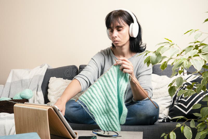 Middle Age Woman at Home Look at Digital Tablet Computer and Knitting ...