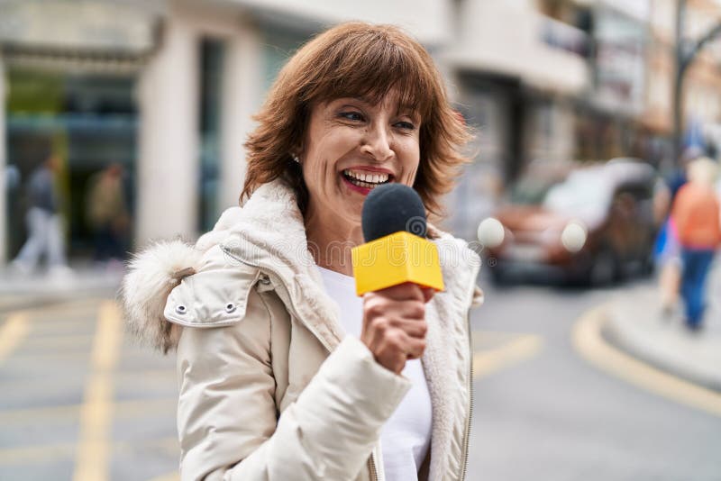 Middle Age Woman Reporter Working Using Microphone at Street Stock ...