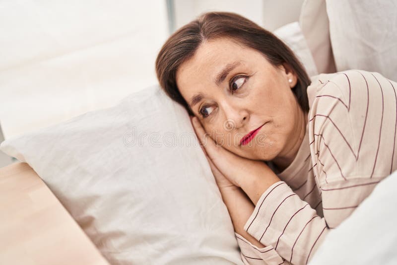 Middle Age Woman with Sad Expression Lying on Bed at Bedroom Stock ...