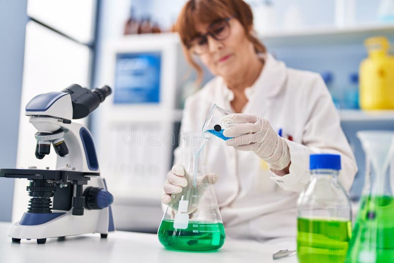 Middle Age Woman Scientist Measuring Liquid at Laboratory Stock Image ...