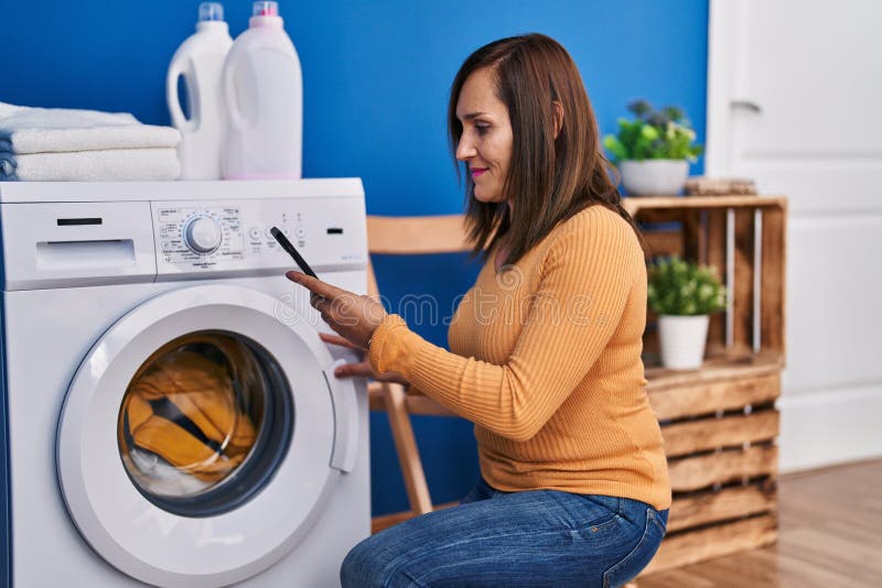 Middle Age Woman Turning on Washing Machine Using Smartphone at Laundry ...