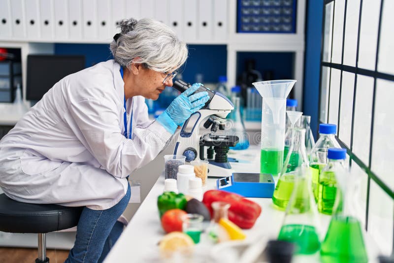 Middle Age Woman Wearing Scientist Uniform Using Microscope at ...