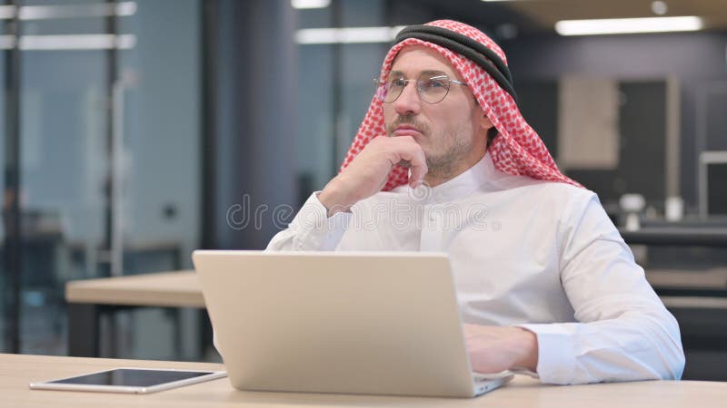 Middle Aged Arab Man Thinking while Using Laptop in Office Stock Photo ...