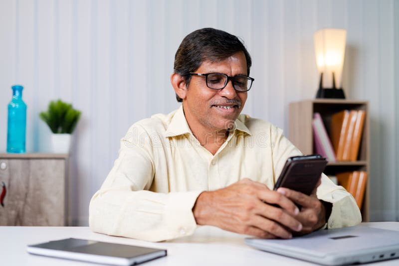 Middle Aged Businessman Smiling while Using Mobile Phone at Office ...
