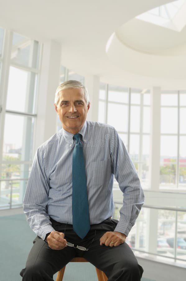 Middle Aged Businessman on Stool in Office Lobby Stock Photo - Image of ...