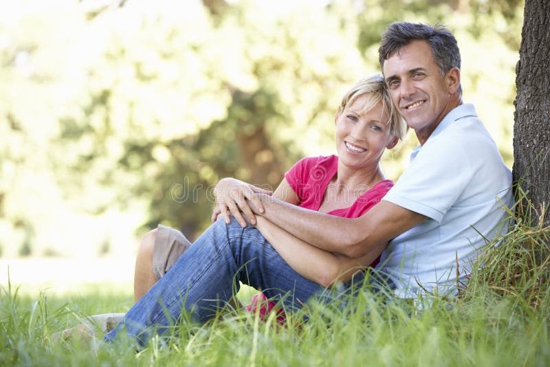 Middle Aged Couple Relaxing in Countryside Leaning Against Tree Stock ...