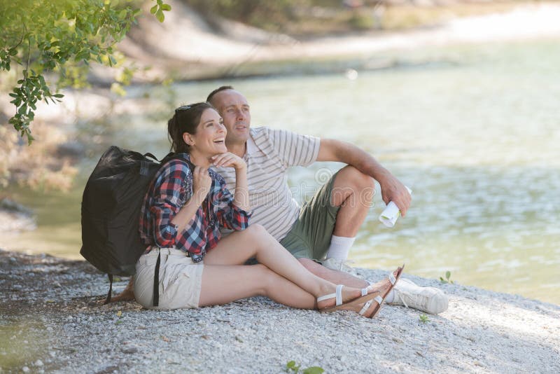 Middle Aged Couple Resting on River Bank Stock Photo - Image of shorts ...