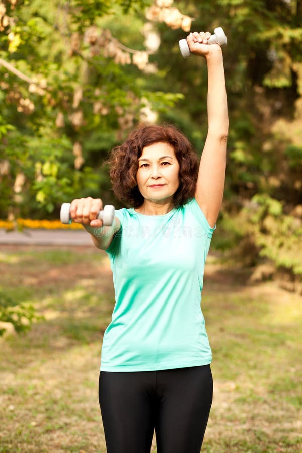 Middle Aged Elderly Active Woman Doing Exercise with Dumbbells in a ...