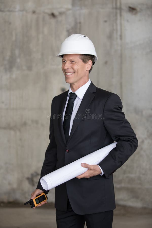 Middle Aged Engineer Holding Blueprint and Walkie-talkie while Looking ...