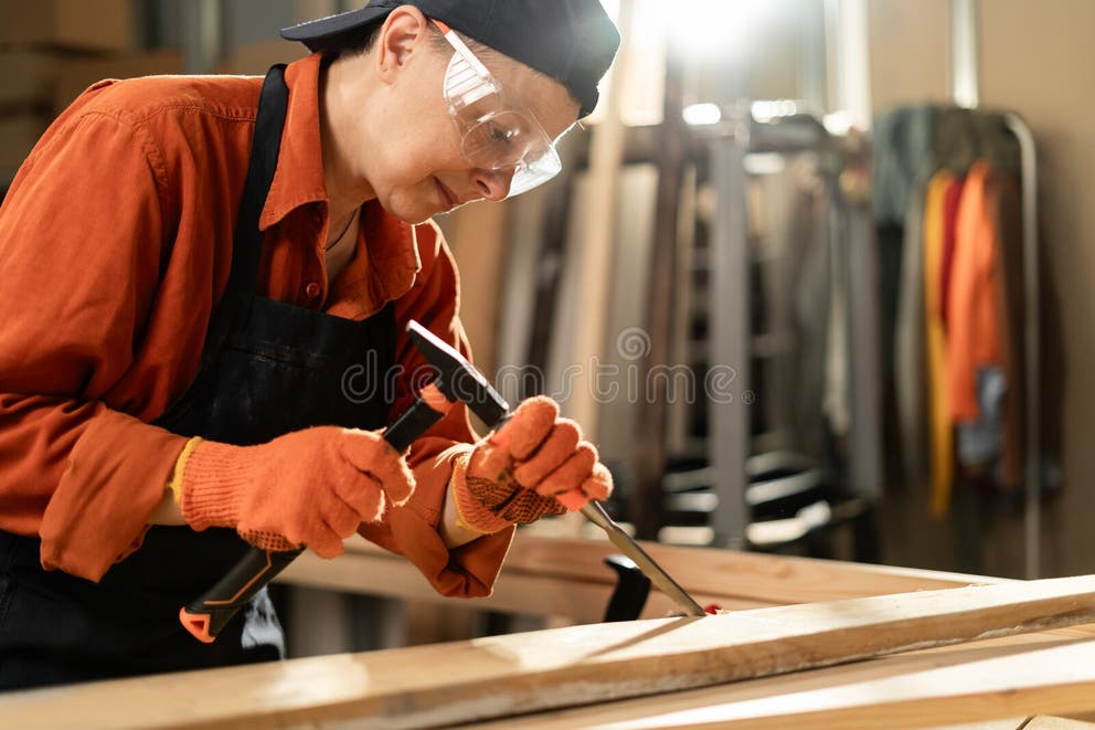 Middle Aged Female Carpenter Using Hammer while Working in a Workshop ...