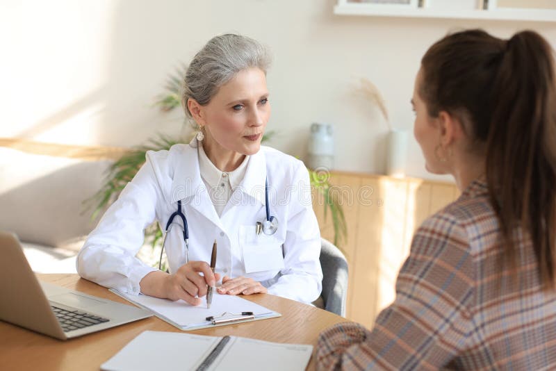 Middle Aged Female Doctor Therapist In Consultation With Patient In
