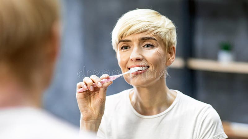 Middle-Aged Lady Brushing Teeth Using Toothbrush Standing in Bathroom ...