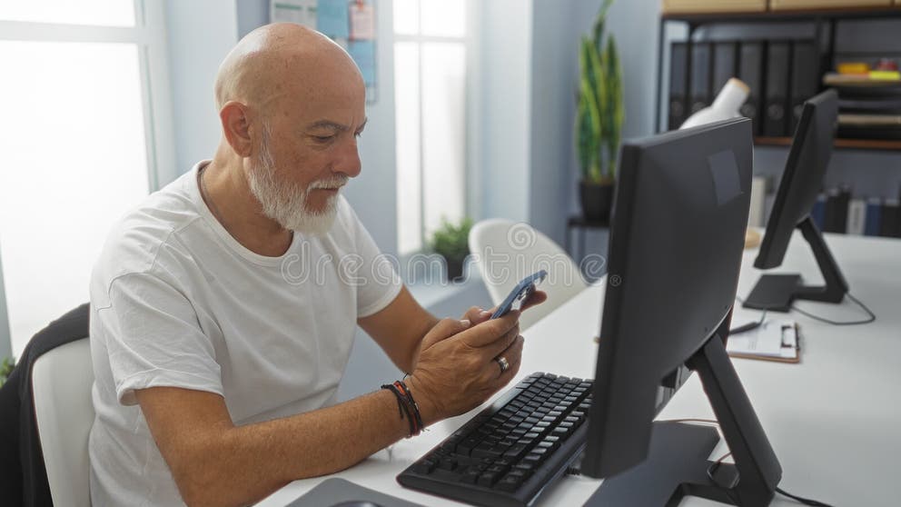 Middle-aged Man with a Bald Head and Grey Beard Using a Smartphone at ...