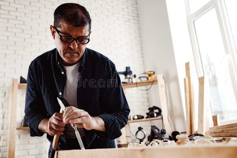 Middle-aged Man Carpenter Working in a Workshop with Chisel and Hammer ...