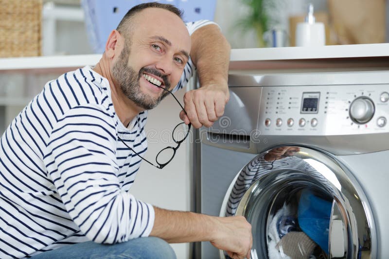 Middle Aged Man Crouched by Washing Machine Stock Image - Image of ...