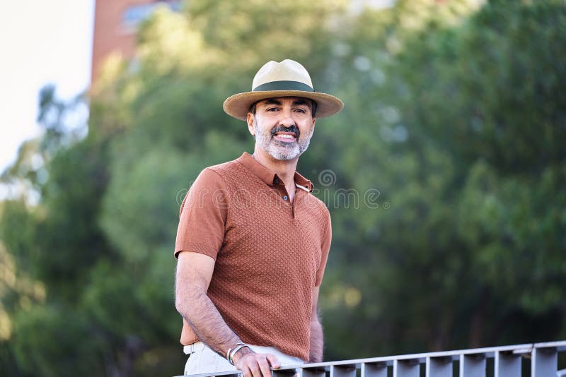 Middle-aged Man in Hat Smiling while Leaning on a Railing Outdoors ...